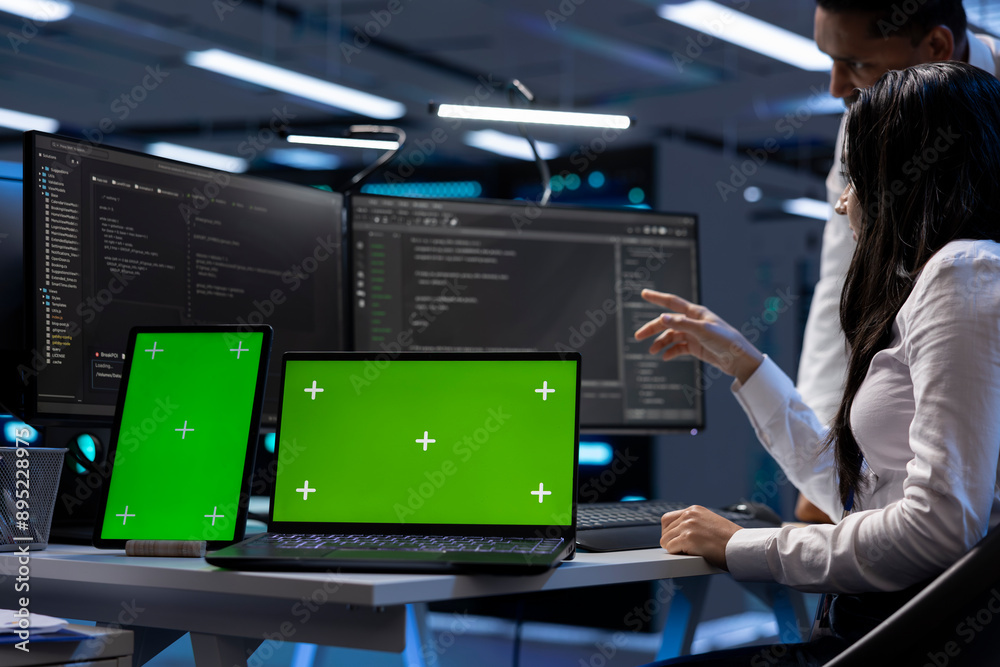 Engineers in data center using mockup tablet and laptop to check for server issues arising due ...
