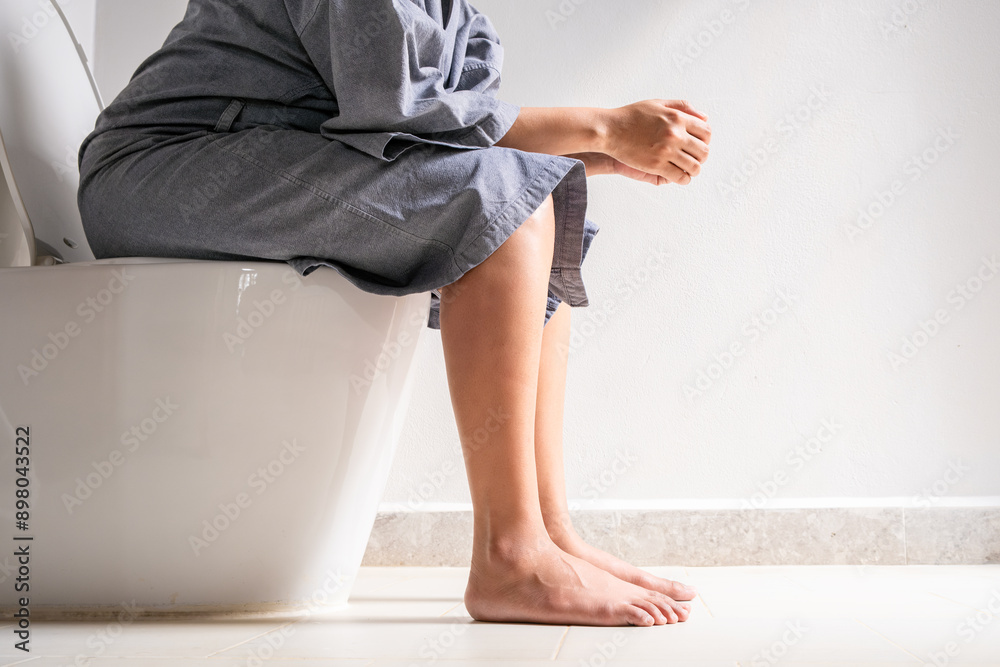 woman sitting on the toilet bowl in the bathroom. she has stomach ache. Poor digestive system ...