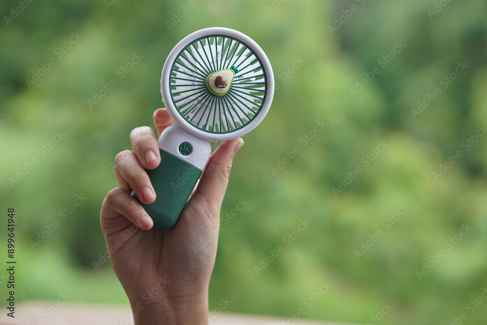 Mini electric fan with handle, outdoor background. Concept , Portable ...