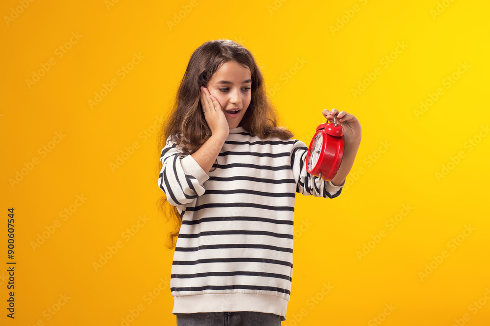 Surprised kid girl holding an alarm clock in hand. The concept of ...