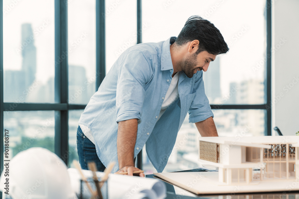 Professional architect engineer inspecting house model while designing building by comparing ...