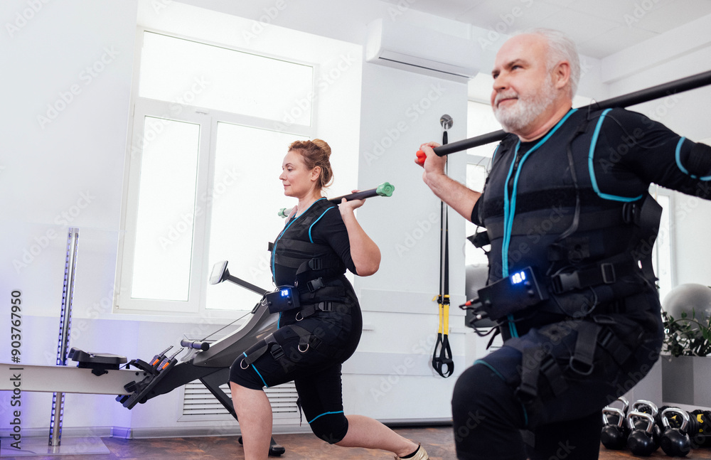 Older sports couple in ems suits doing electrical muscle stimulation ...