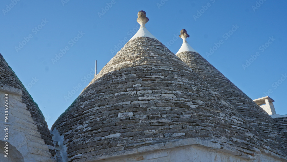 Traditional trulli houses with conical roofs under a clear blue sky in ...