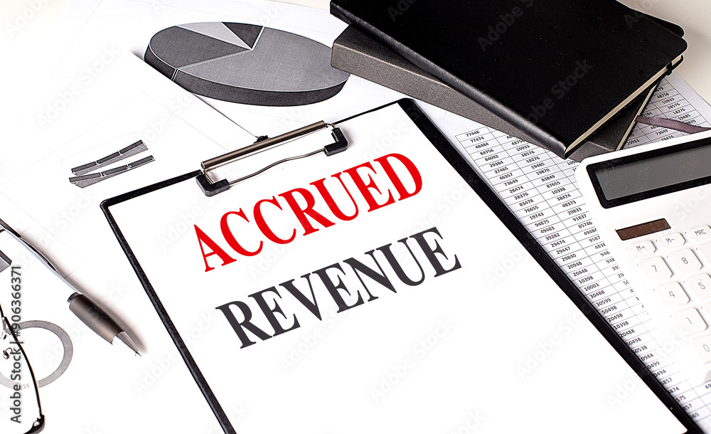 ACCRUED REVENUE text on clipboard on chart with notebook and calculator ...