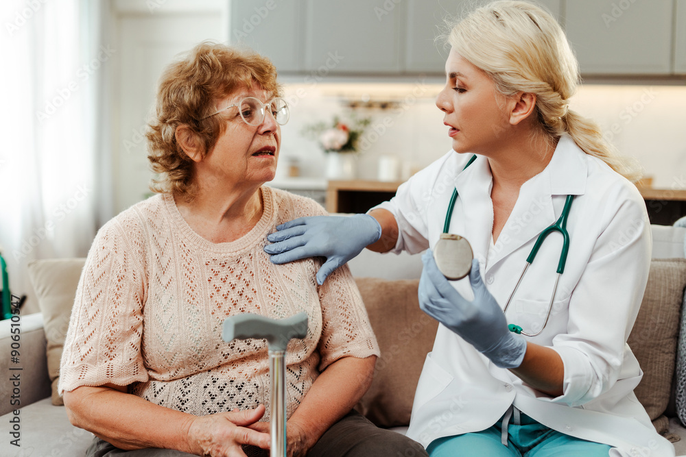 Attractive female doctor holding pacemaker, showing to senior patient ...