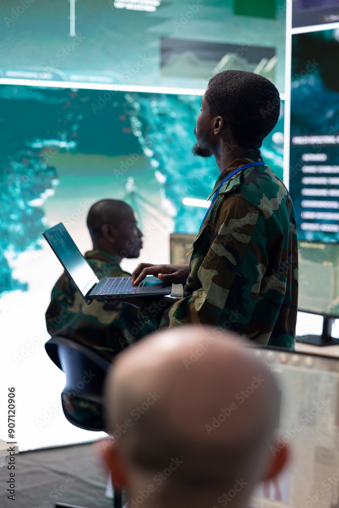 Military recruit reviewing radar surveillance footage on a big screen ...