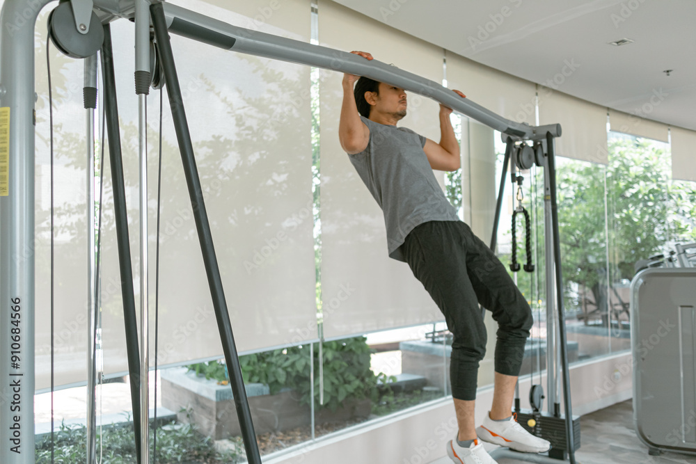 Side view of asian fitness man hanging on pull-up bar at gym, gaining ...