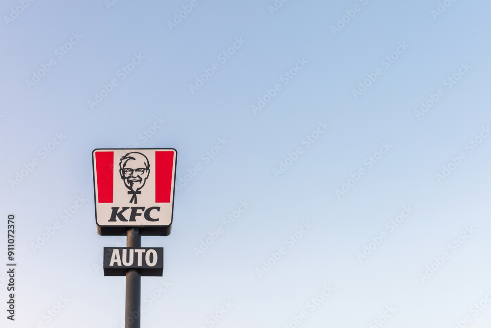 Iconic KFC sign mounted on a pole against a clear blue sky ...