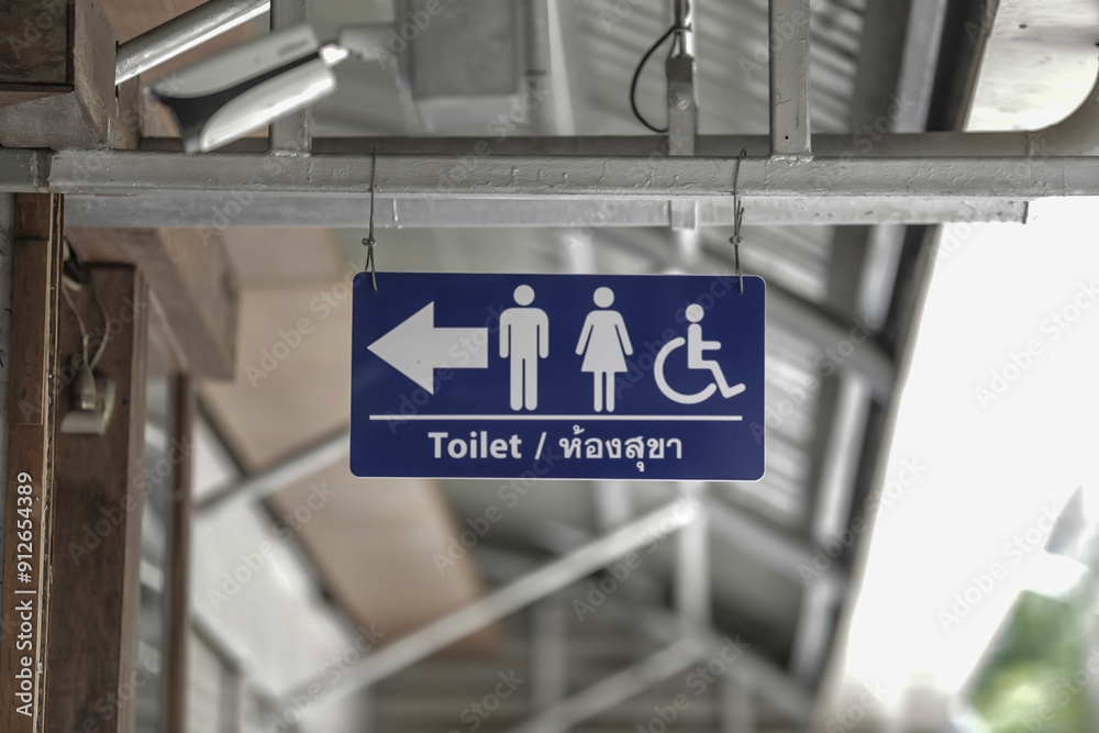 toilet sign with arrow blue and white hanging on the ceiling day time ...