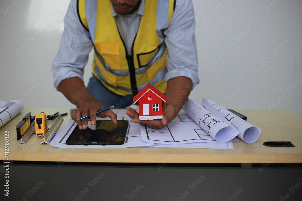 Asian architect and designer using blueprints and laptop to draw ...