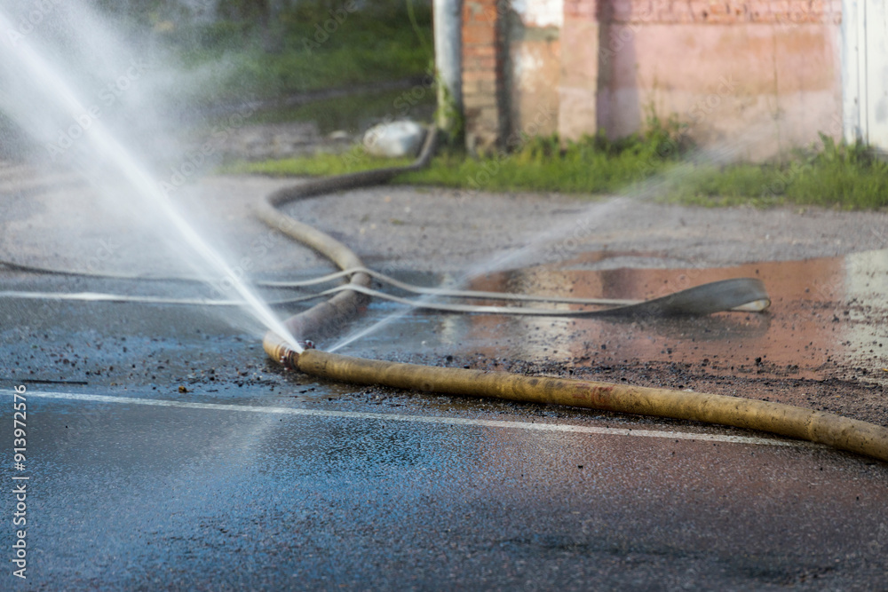 Water gushes from a coiled fire hose, creating a refreshing spray on ...