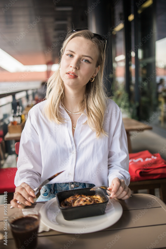 Blonde gen z woman eating lasagna in the cafe on break. Gen z girl ...