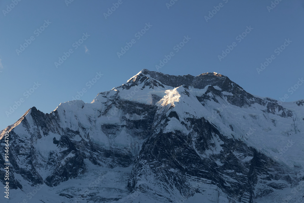 The snow-capped peak of mount everest is bathed in golden light ...