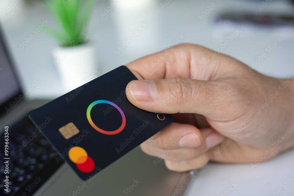 Man hand holding plastic card Payoneer Mastercard laptop Apple Macbook ...