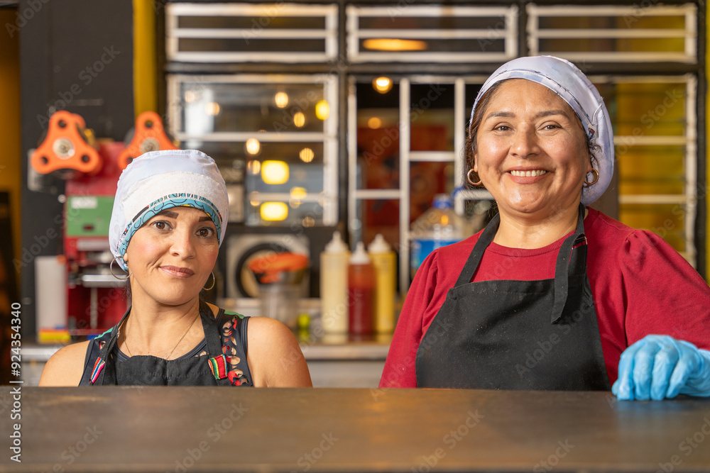 Two happy cooks smiling behind counter in a fast food restaurant ...