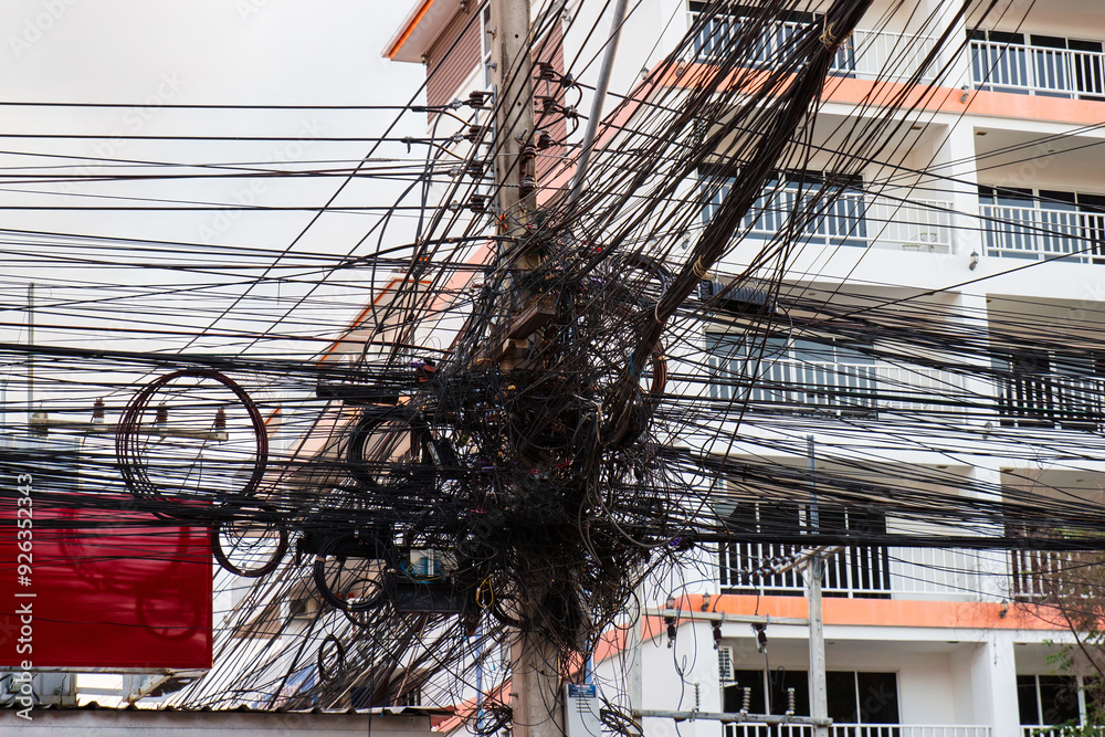 Messy chaos from cables and wires on electric pole. A typical situation ...