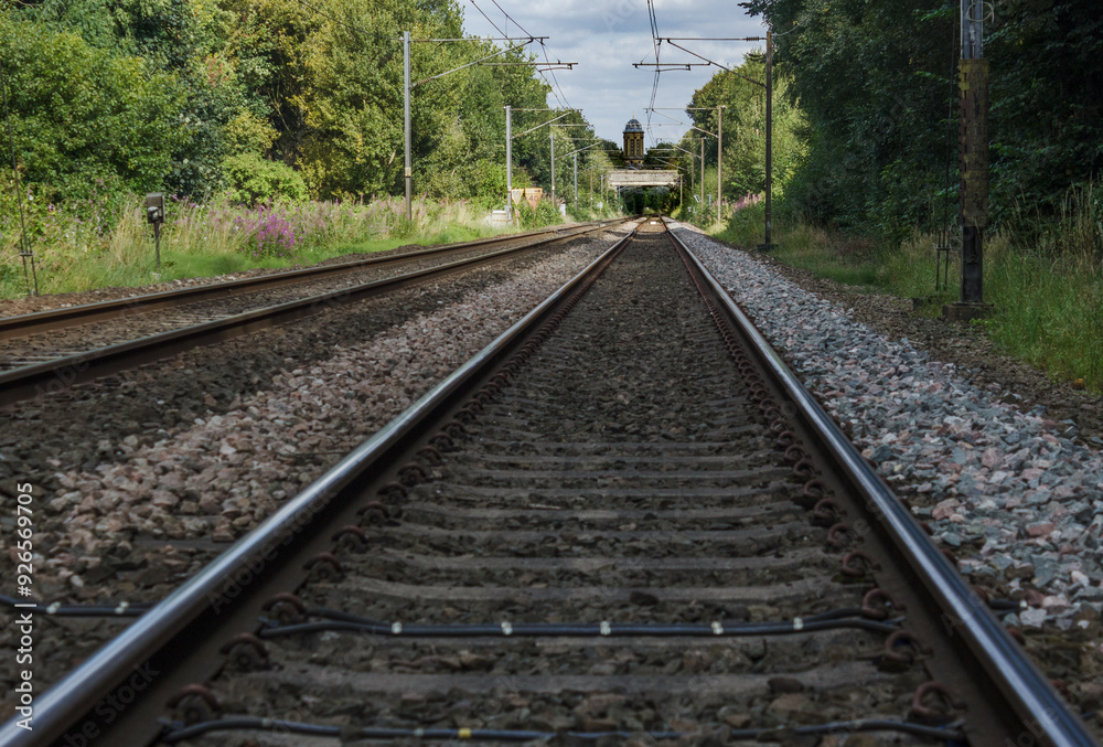 Parallel railway tracks heading towards a church tower at the vanishing ...
