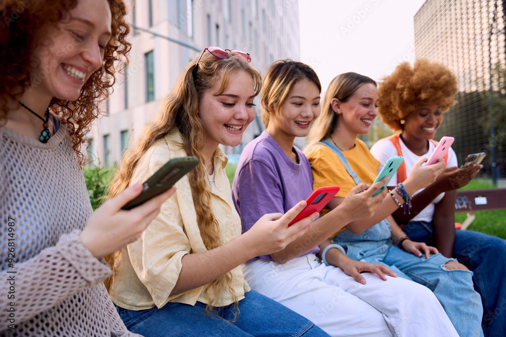 Group of young women using a mobile cell while having fun in the park ...