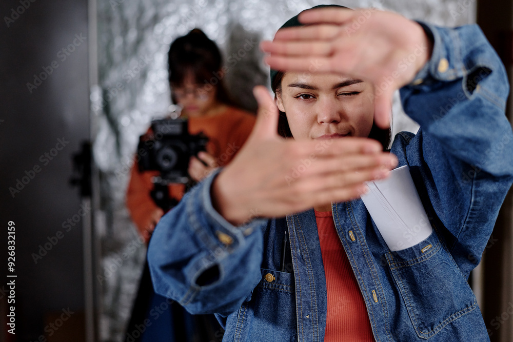 Person forming frame with fingers while standing in photography studio ...