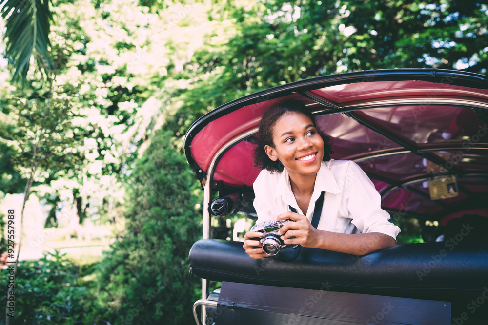happy black traveler girl using camera outside tuk tuk ride. solo ...