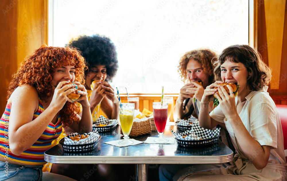 Multiethnic group of friends having meal at 80s vintage diner ...