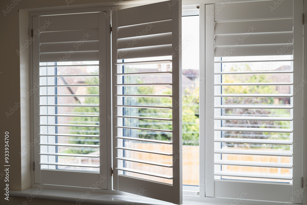 Three frames of white modern wooden shutters across a window. One ...
