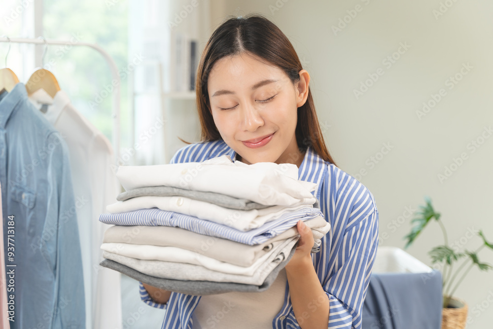 Smile happy asian housewife smelling the scent of fresh clean clothes ...