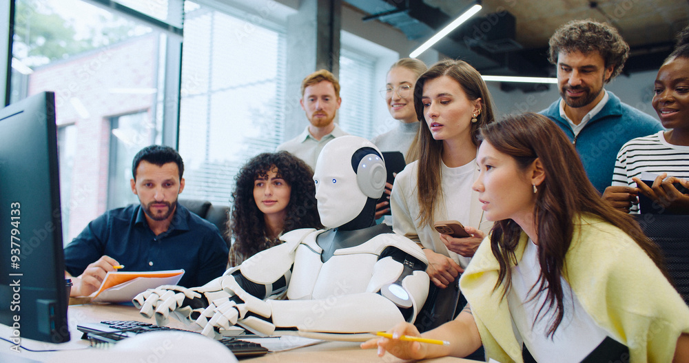 Multi-ethnic group of smart engineers looking at their robot entering text. Checking if program ...