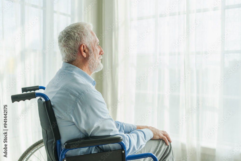 Sad senior man sitting in wheelchair looking out window in retirement ...
