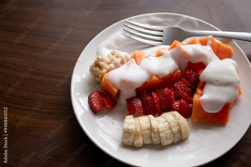 Fruta picada con yogurt y tenedor para desayunar sobre mesa de madera y ...