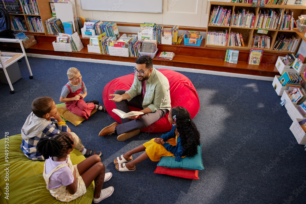 Friendly teacher reading a book to pupils during literature class Stock ...