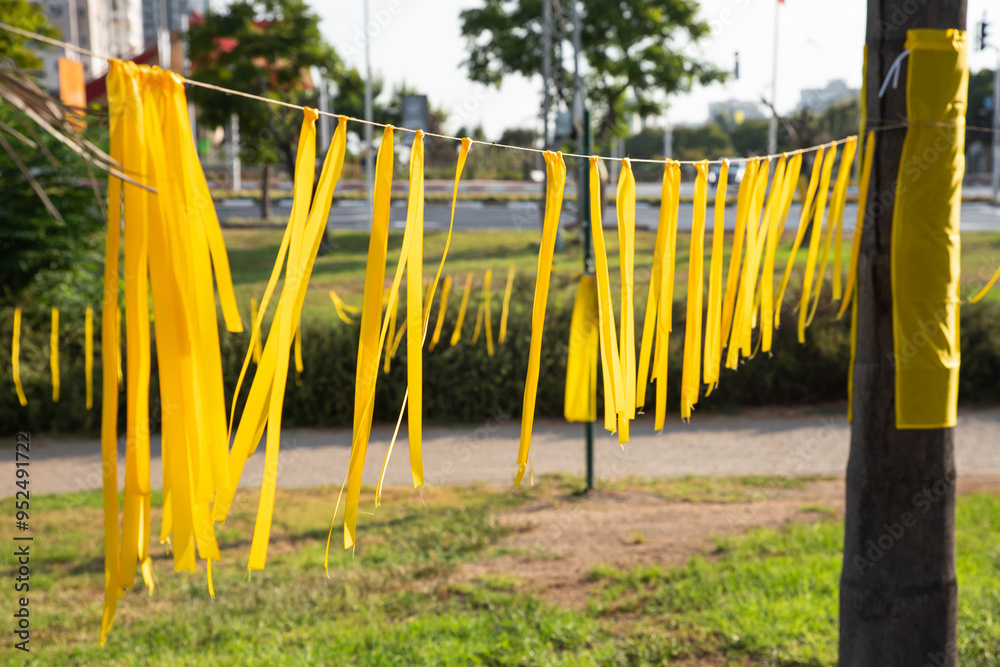 Installation of yellow ribbons in a park, tied between trees as a ...