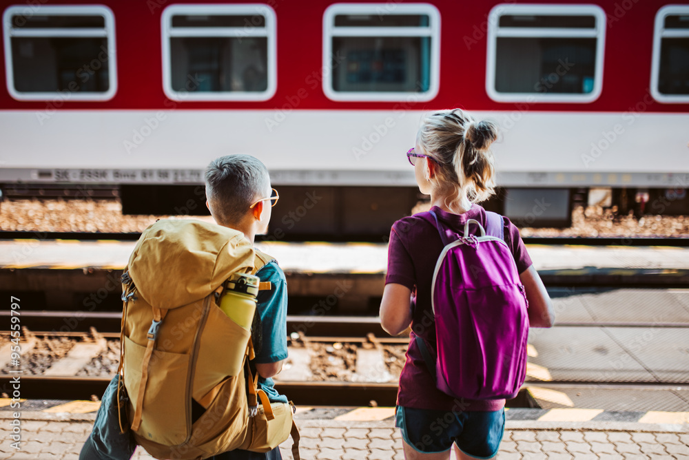Siblings waiting for train, standing on platform. Family going on hike ...
