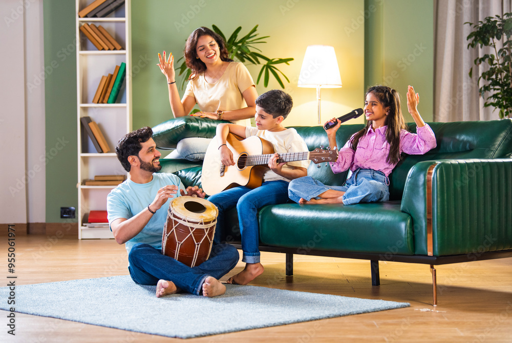Happy Indian Asian family making music together at home; singing ...