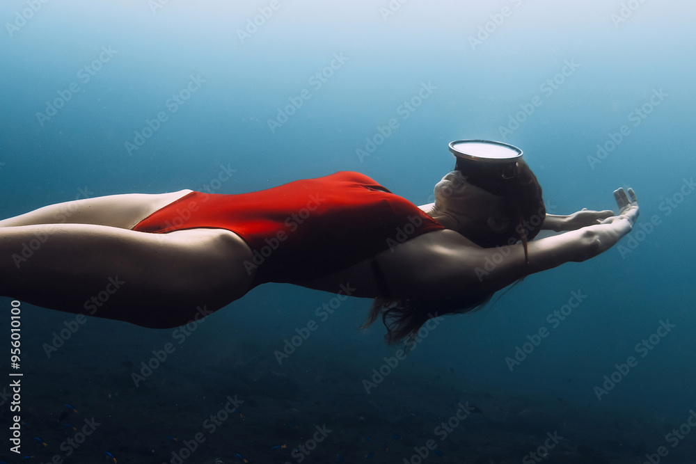 Young gorgeous woman freediver in red swimwear swims underwater in deep ocean. Sexy woman ...