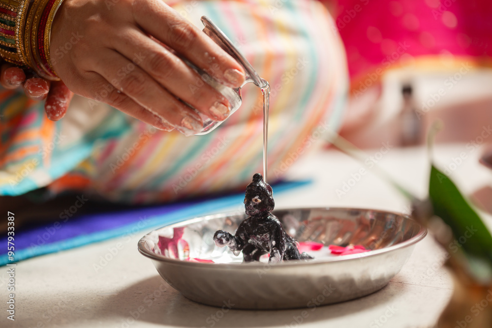 Indian woman performing snan ritual by pouring 'Ganga Jal' on (Laddu ...