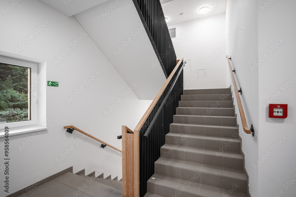 A modern interior staircase with wooden handrails, tiled steps, and an ...