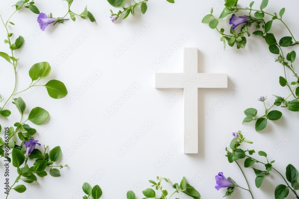 A simple white wooden cross with green leaves and purple flowers, on a ...