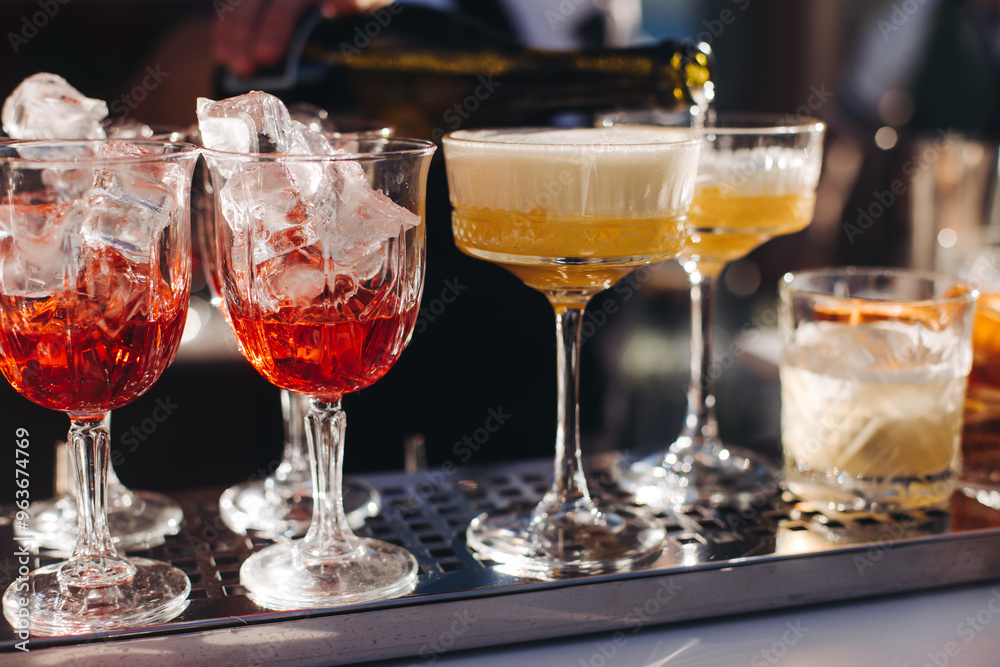 Bartender working, beautiful row line of different coloured liquor ...