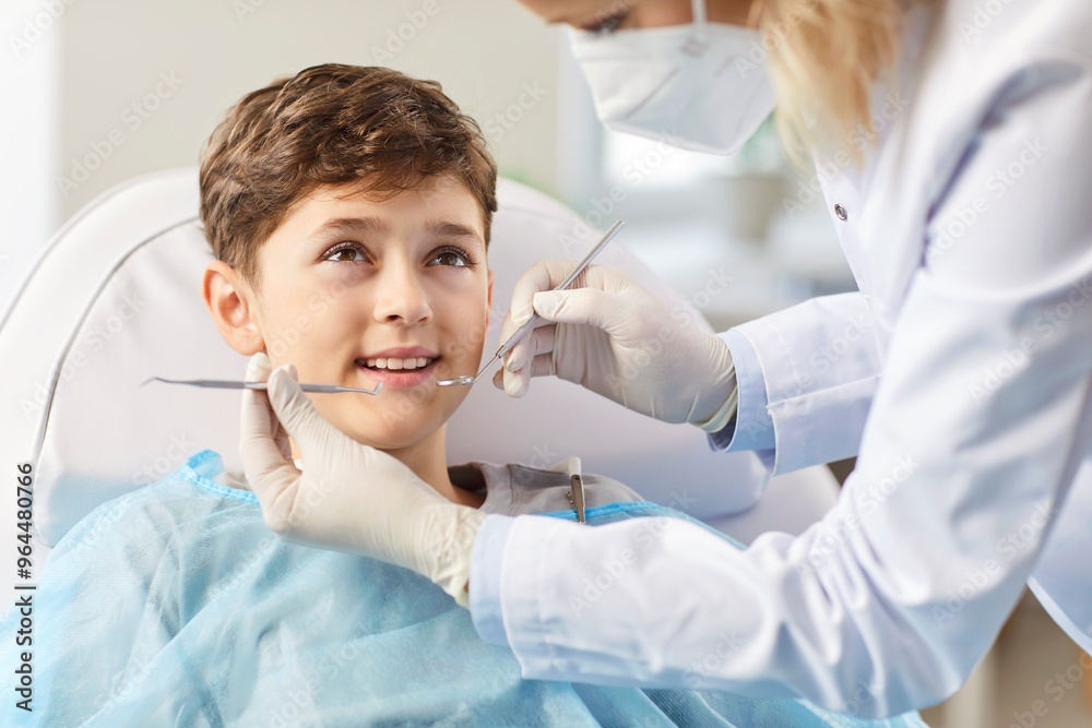 Dentist examines a boy patient teeth during a medical visit to the ...