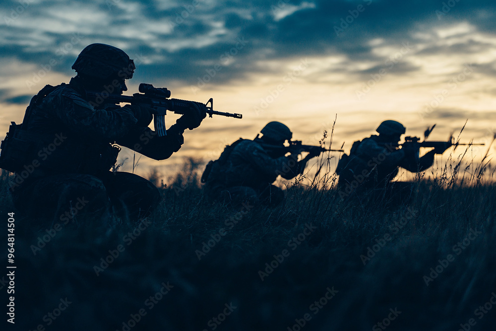 Three soldiers crouching in tall grass with rifles aiming at sunset ...