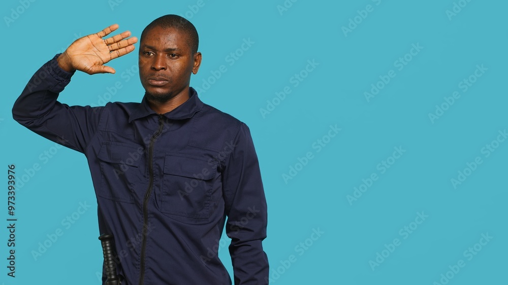 Portrait of security guard scratching head with baton while overseeing ...
