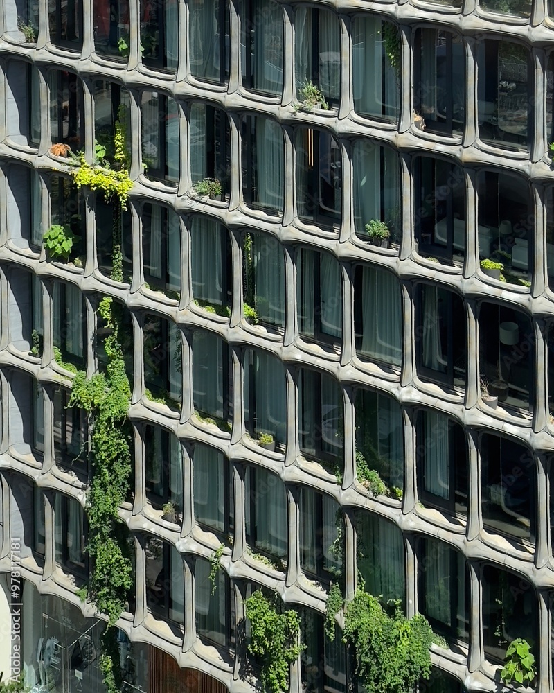 Modern building facade with curvilinear windows and integrated greenery ...