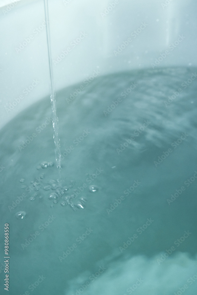 Water is flowing into the tank. Close-up green-blue water texture in a ...