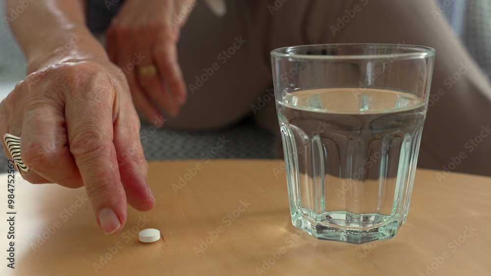 Elderly woman taking medication at home, a routine daily activity ...