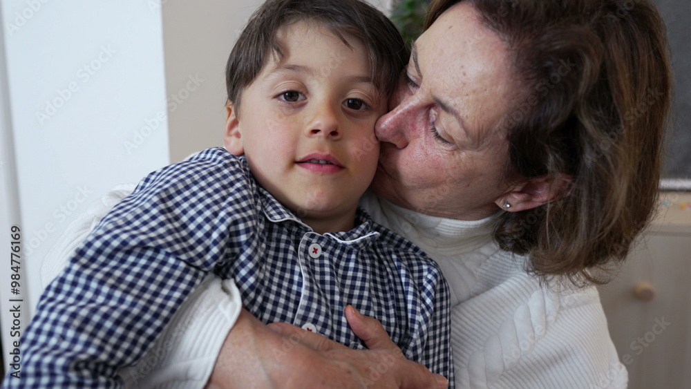 Grandmother gently kissing her grandson on the cheek while holding him ...