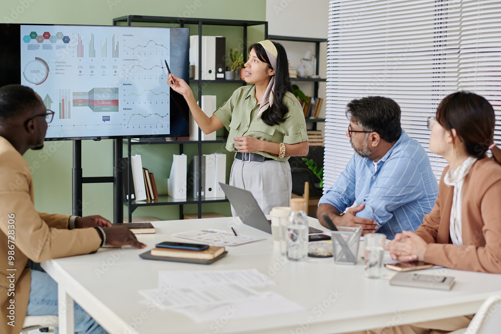 Group of colleagues discussing business data in meeting room with ...