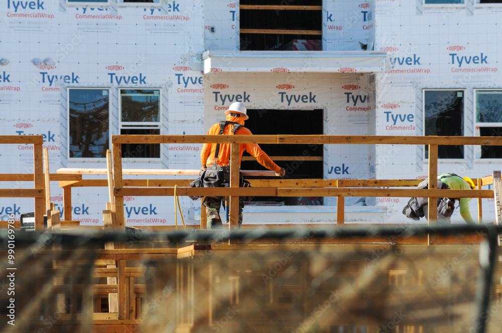 Construction workers stand on scaffolding, working on an apartment ...