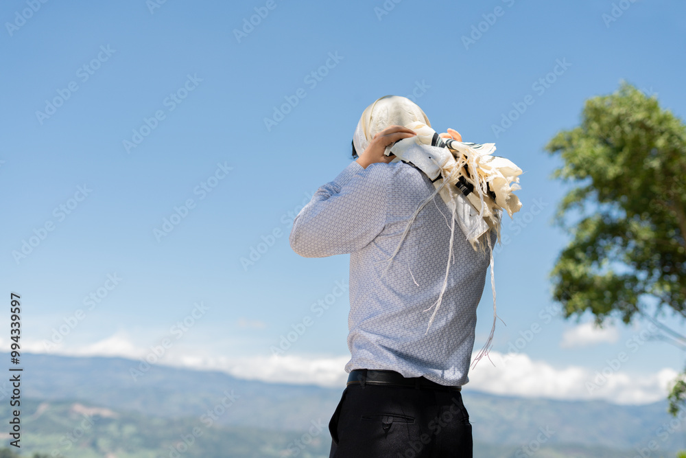 Young Jewish man covering his face with the tallit outdoors with the ...
