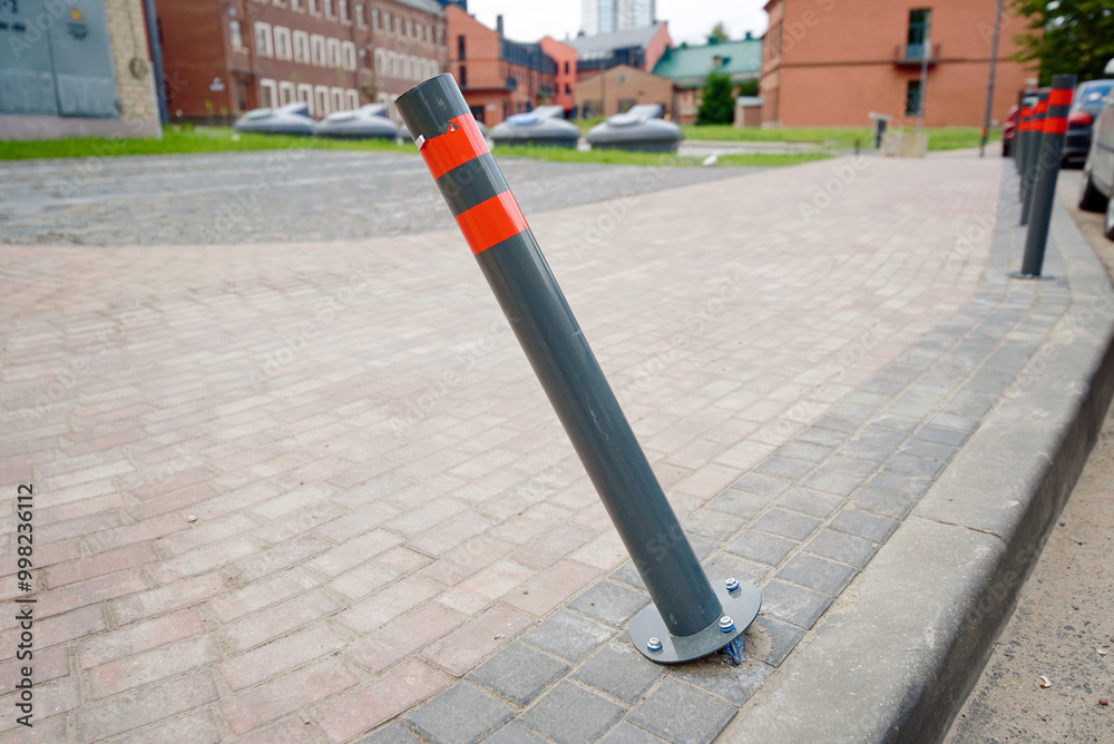 Damaged safety bollard on brick paved street, road security, vehicle ...